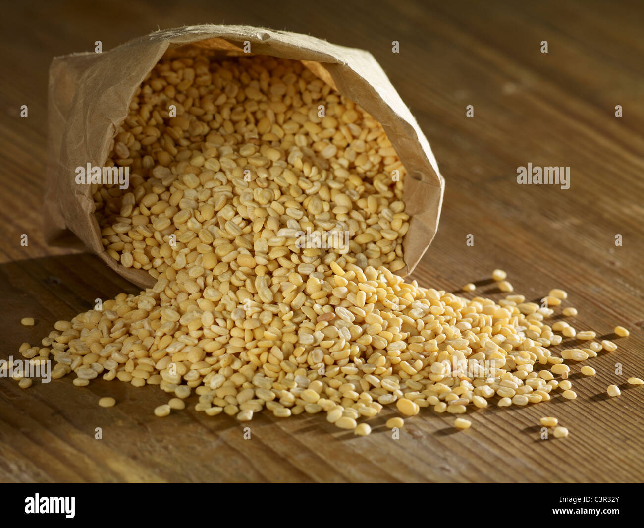 Split mung beans spilling on wooden surface Stock Photo - Alamy