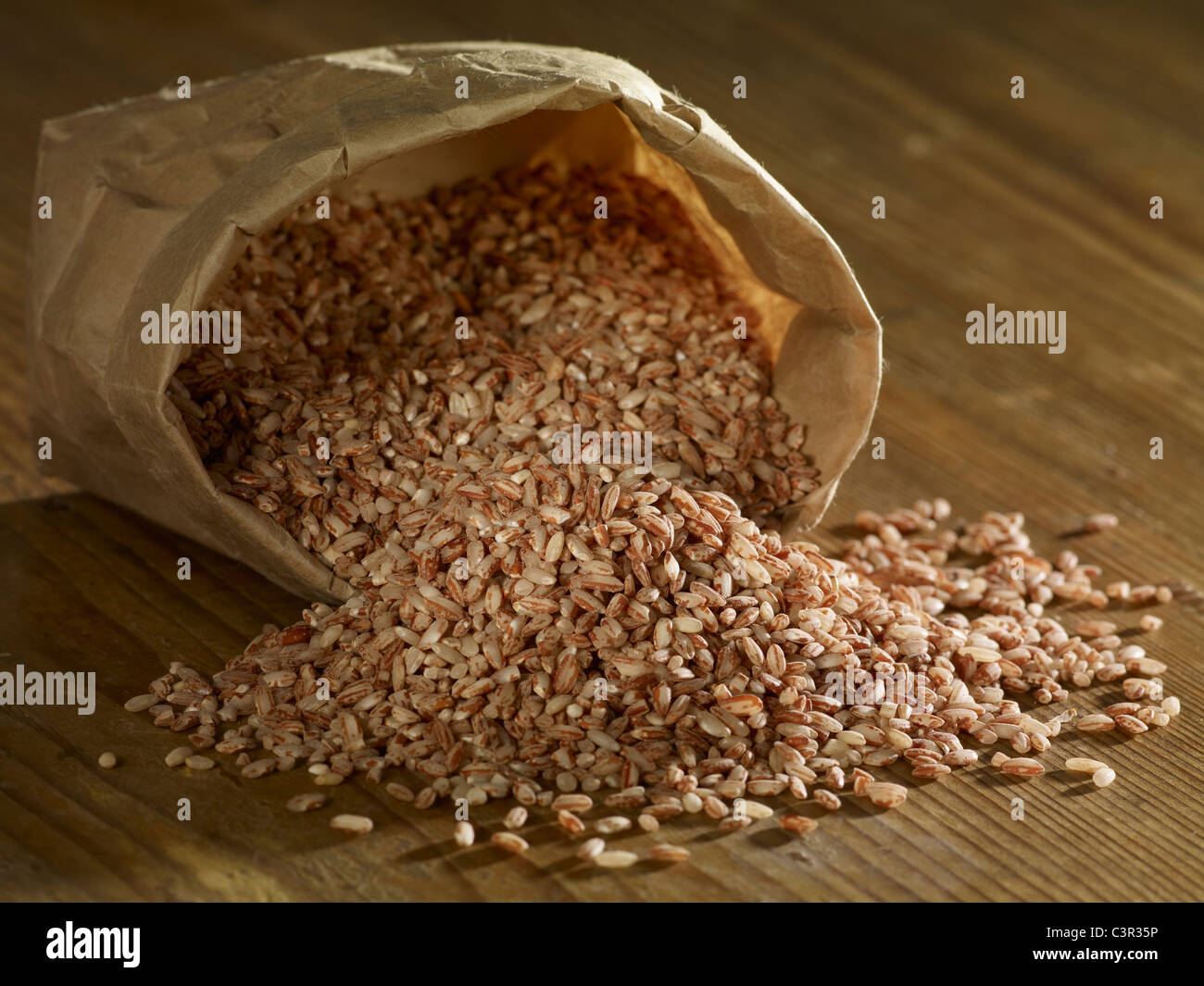 Red rice spilling on wooden surface Stock Photo - Alamy
