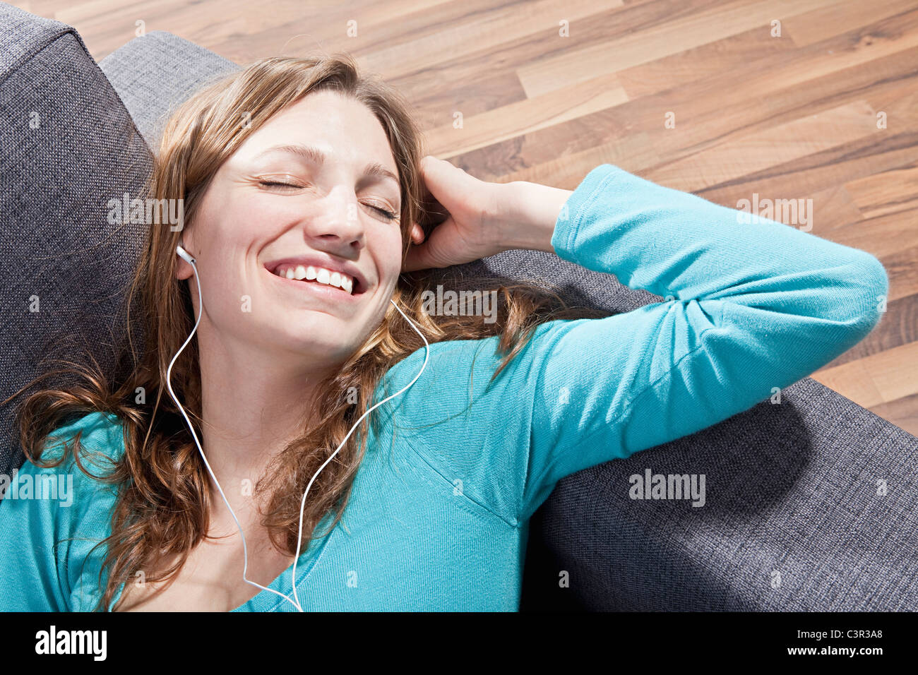 Woman relaxing on couch and listening music, smiling Stock Photo - Alamy