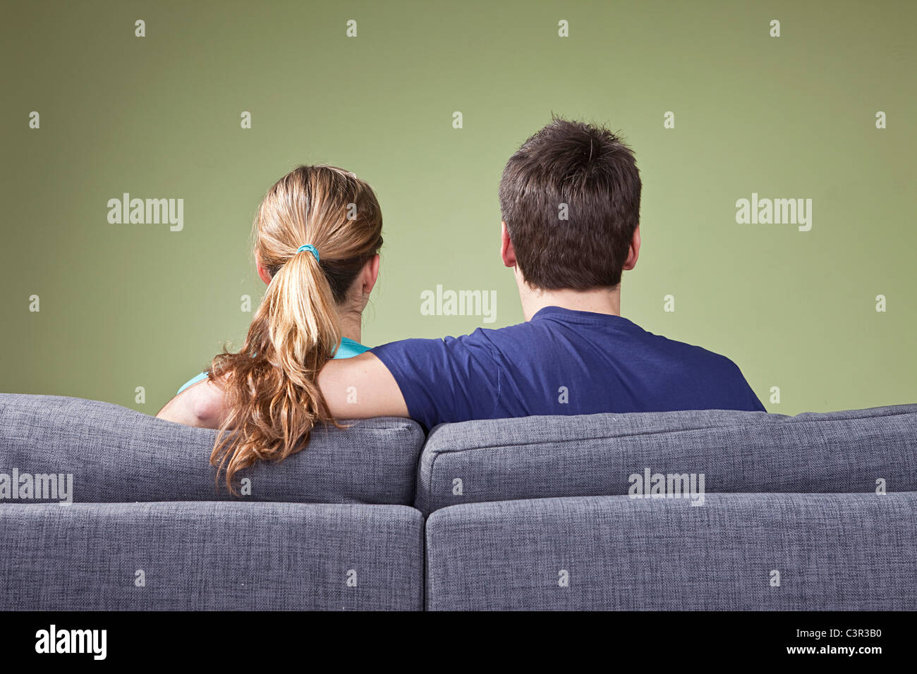 Young couple sitting on couch, rear view Stock Photo - Alamy