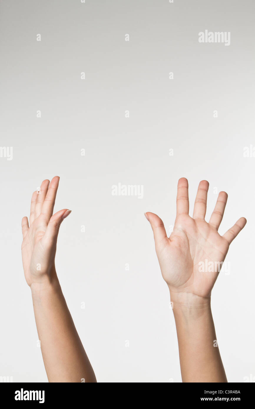 Woman raising hands against white background Stock Photo - Alamy