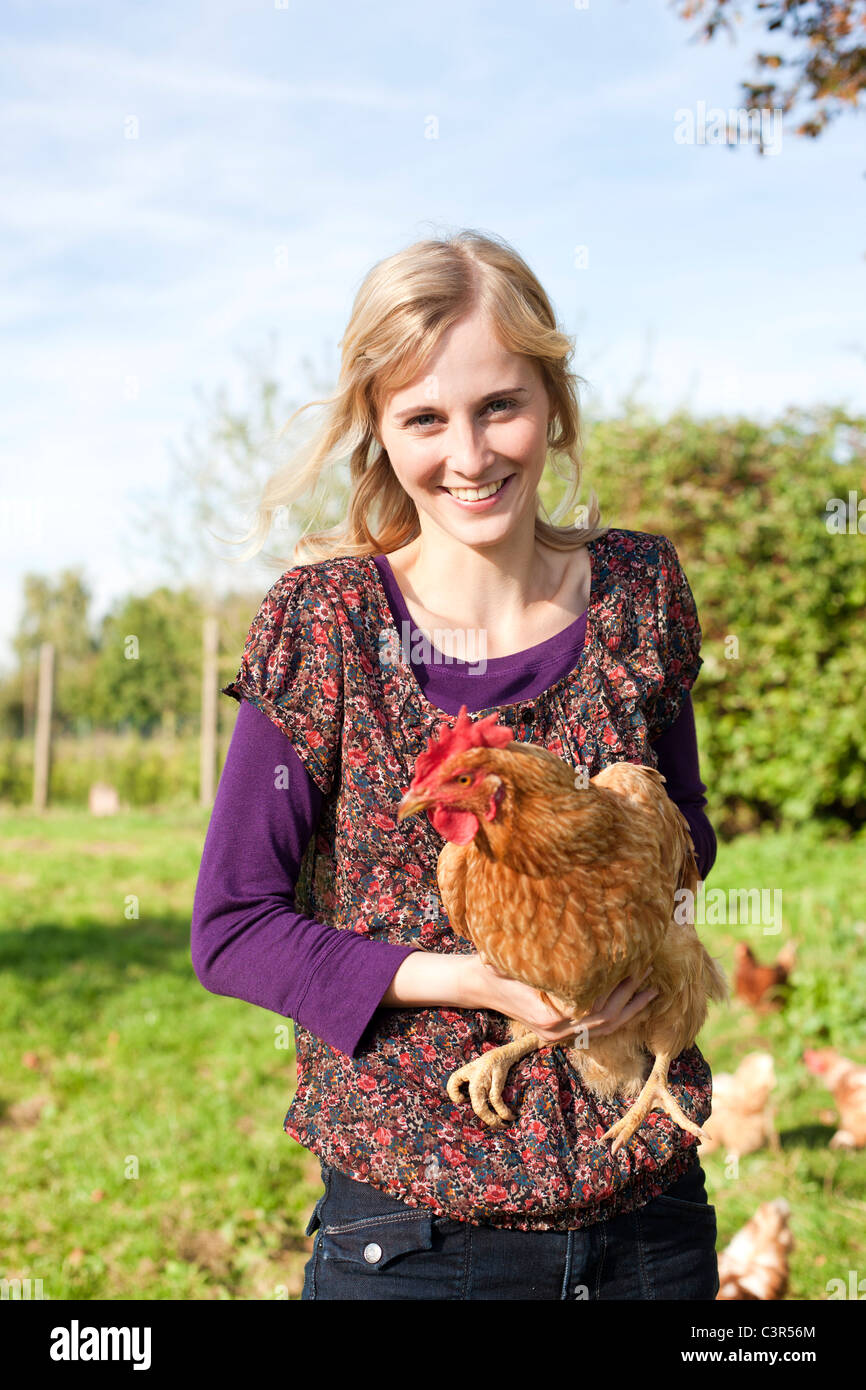 Germany, Saxony, Young woman with hens, portrait, smiling Stock Photo ...