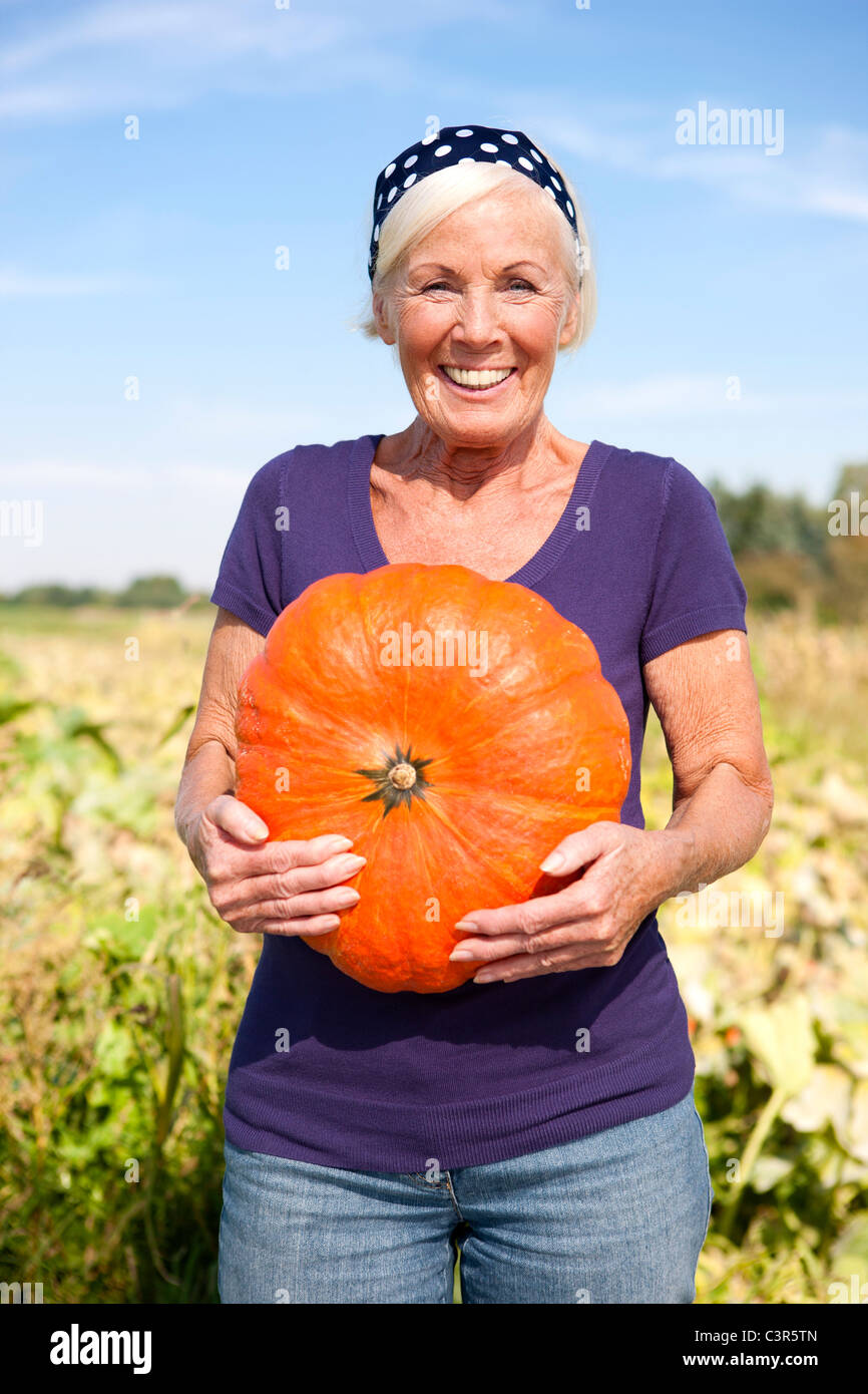 Germany, Saxony, Senior woman carrying pumpkin, smiling, portrait Stock ...