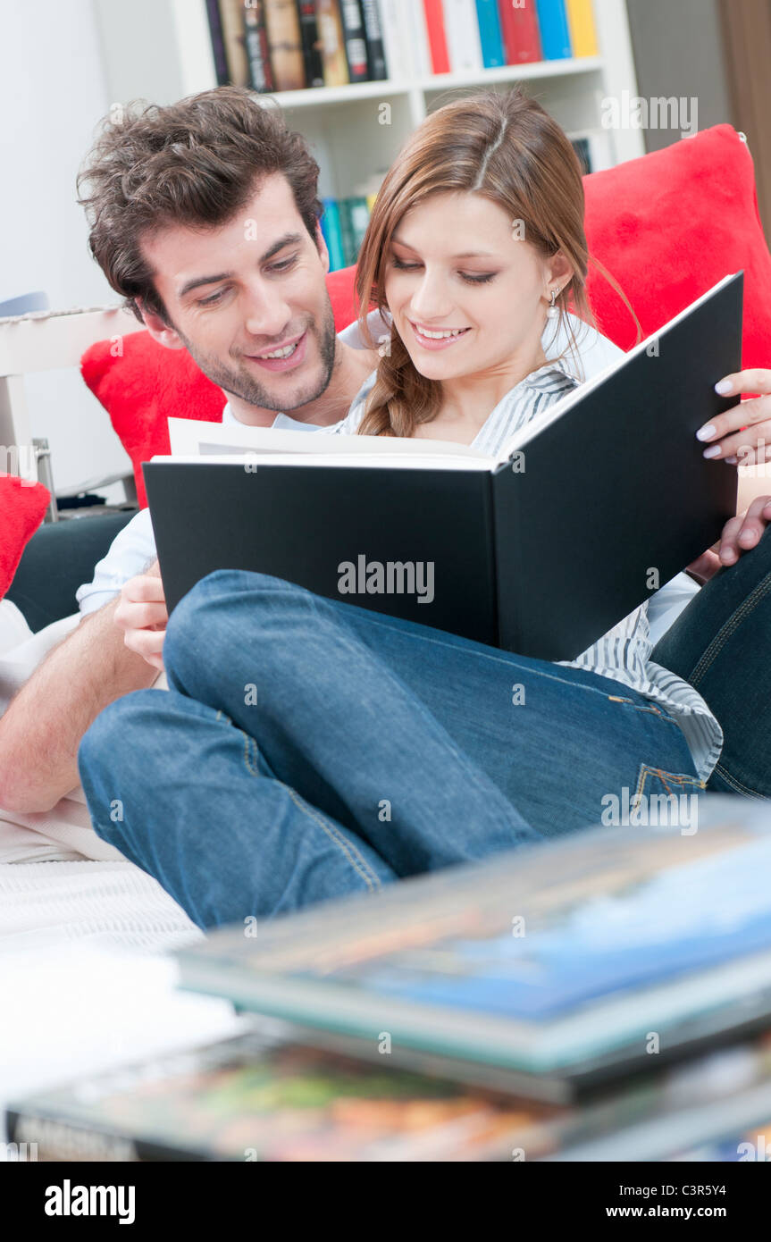 Couple reading together a book on sofa Stock Photo - Alamy