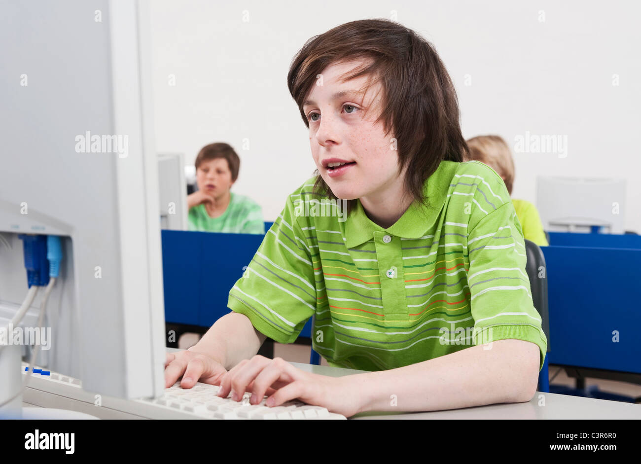 Germany, Emmering, Boy (12-13) using computer with students in ...