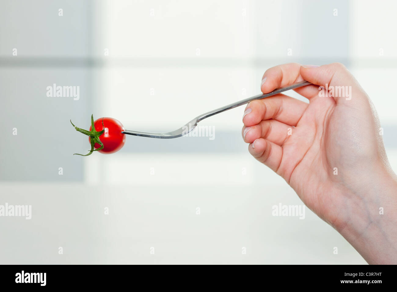Germany, Cologne, Human hand holding tomato on fork Stock Photo - Alamy