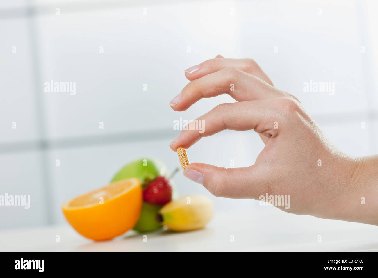 Germany, Cologne, Human hand holding diet pill with fruits in ...