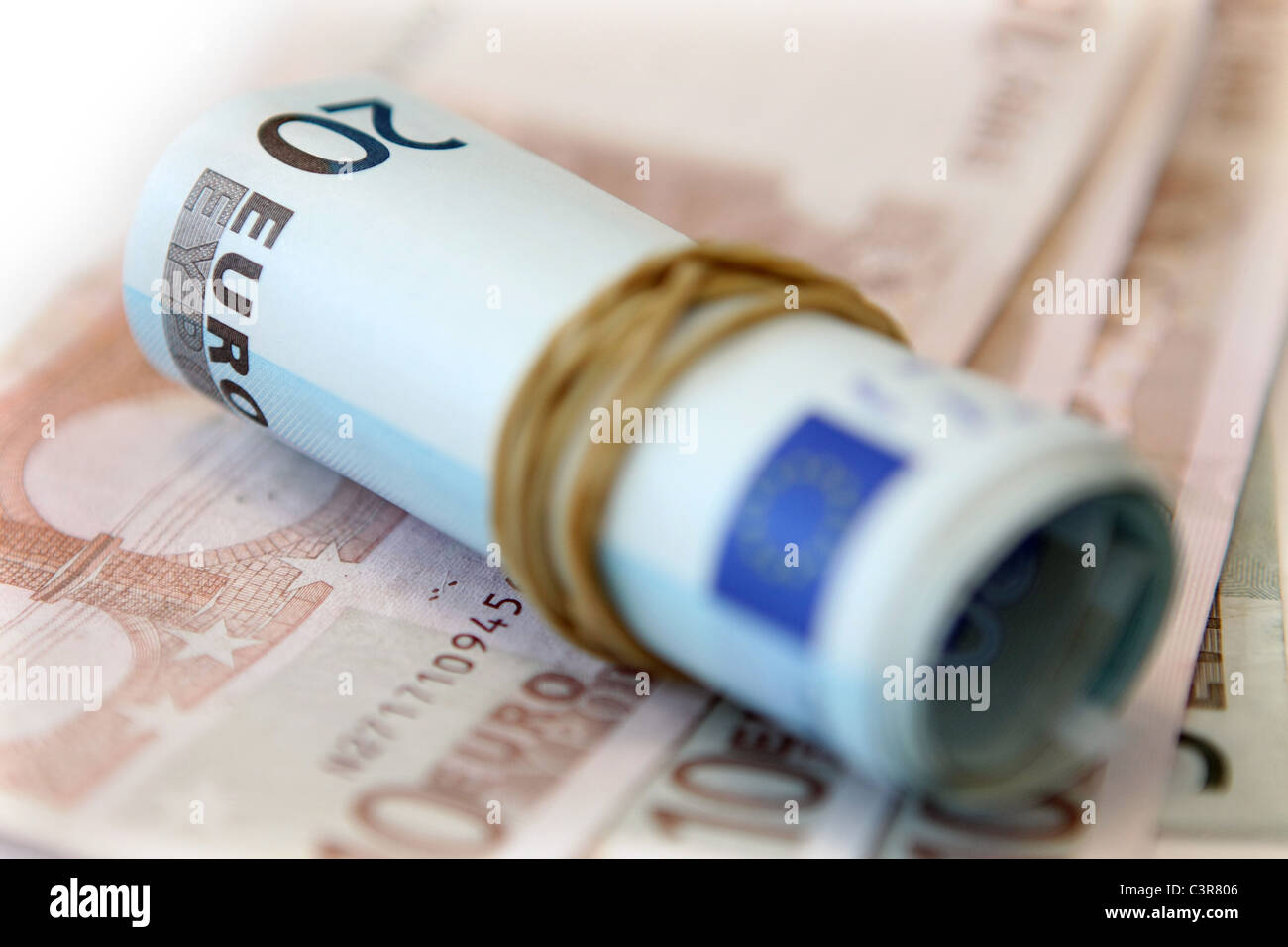 rolled up 20 euro notes in an elastic band on out of focus 10 euro ...