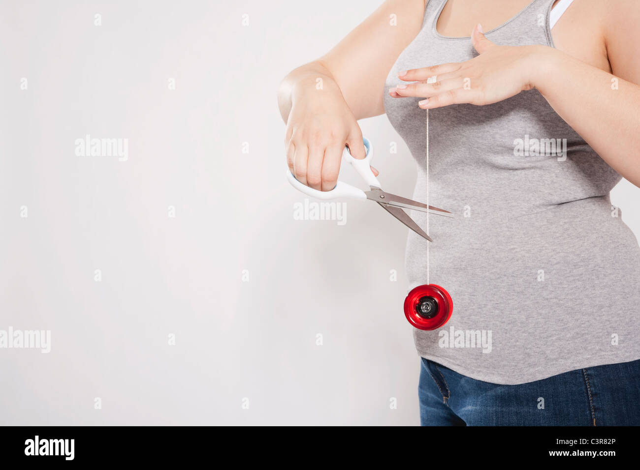 Germany, Cologne, Young woman cutting yo-yo string Stock Photo - Alamy