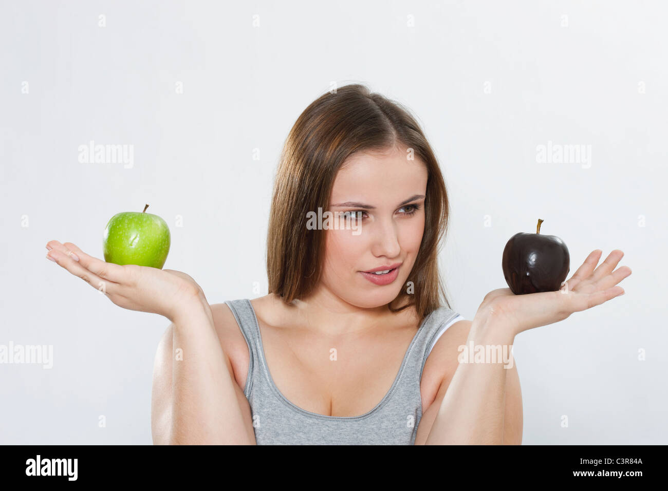 Young woman confused between green apple and chocolate coated apple ...