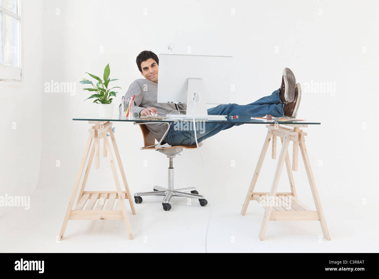 Man working at computer with his feet up Stock Photo - Alamy
