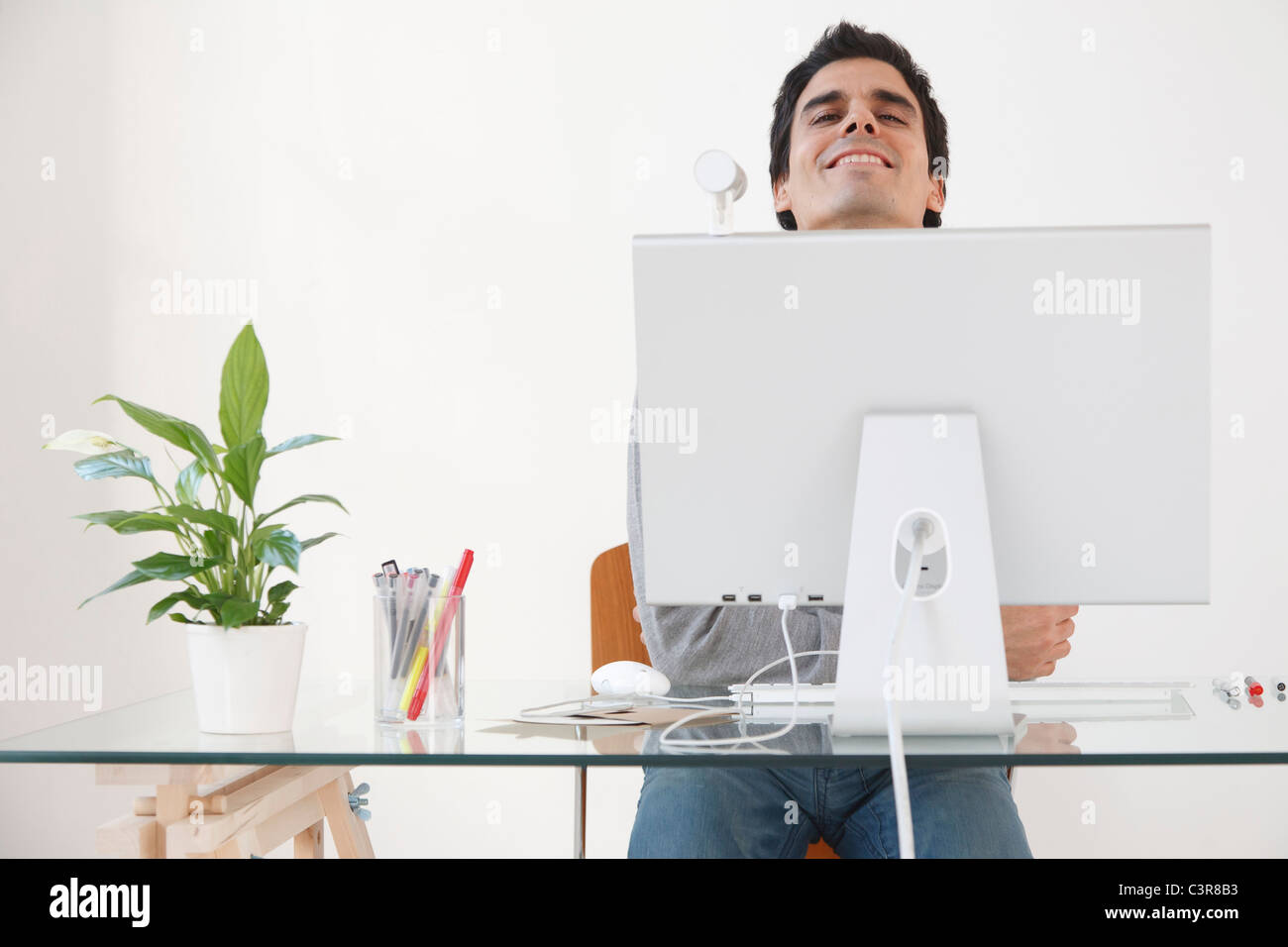 Man working at computer smiling Stock Photo - Alamy