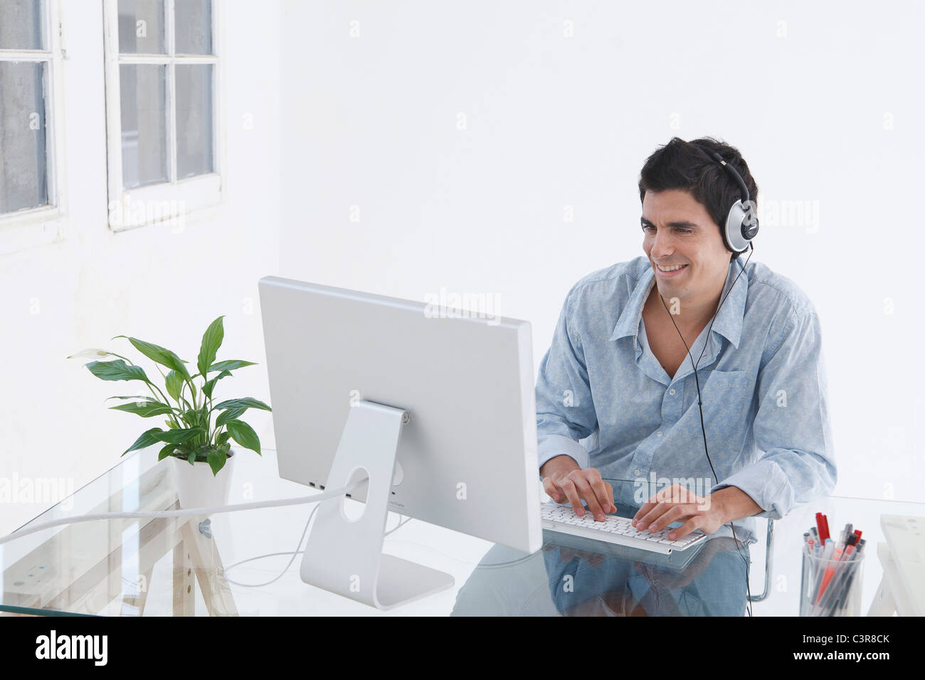 Smiling man headphones typing hi-res stock photography and images - Alamy