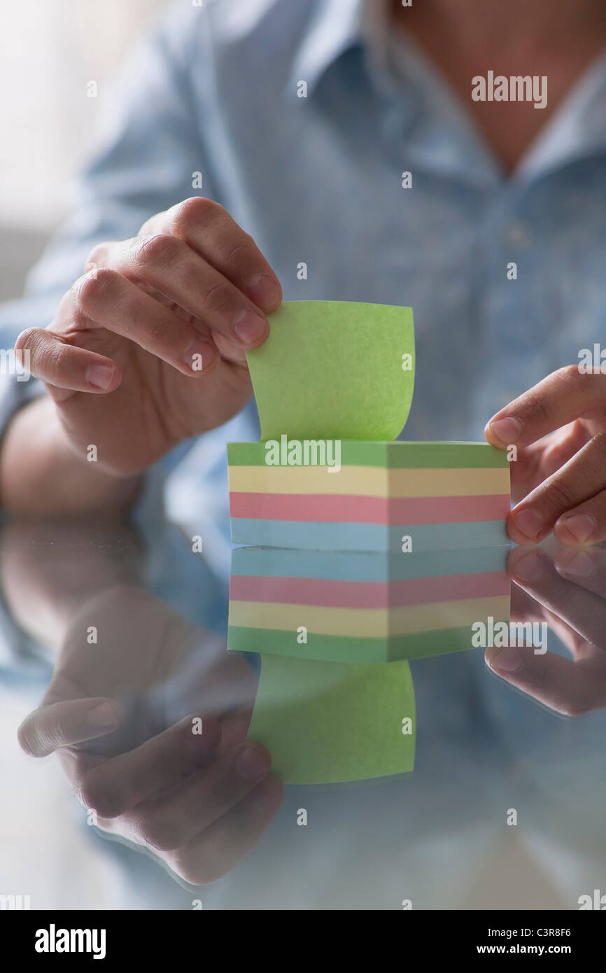 close up of a man picking up a post-it note Stock Photo - Alamy