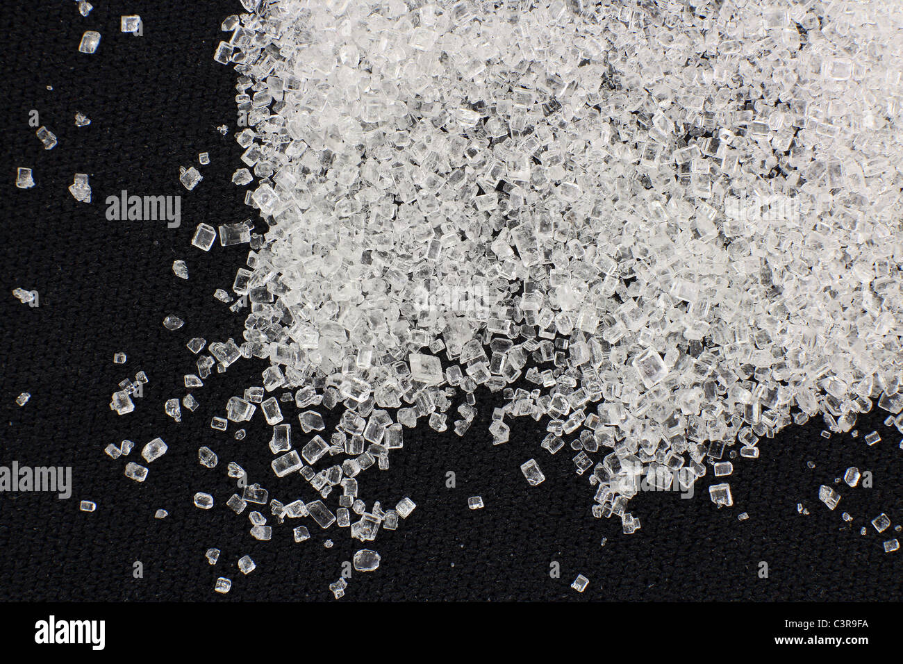 White sugar grains on black background Stock Photo - Alamy