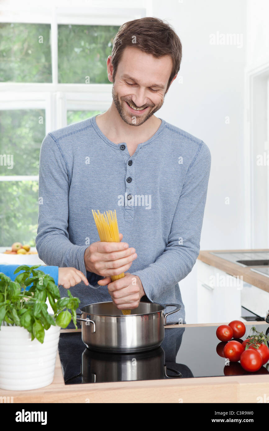 Germany, Bavaria, Munich, Man cooking spaghetti in kitchen Stock Photo ...