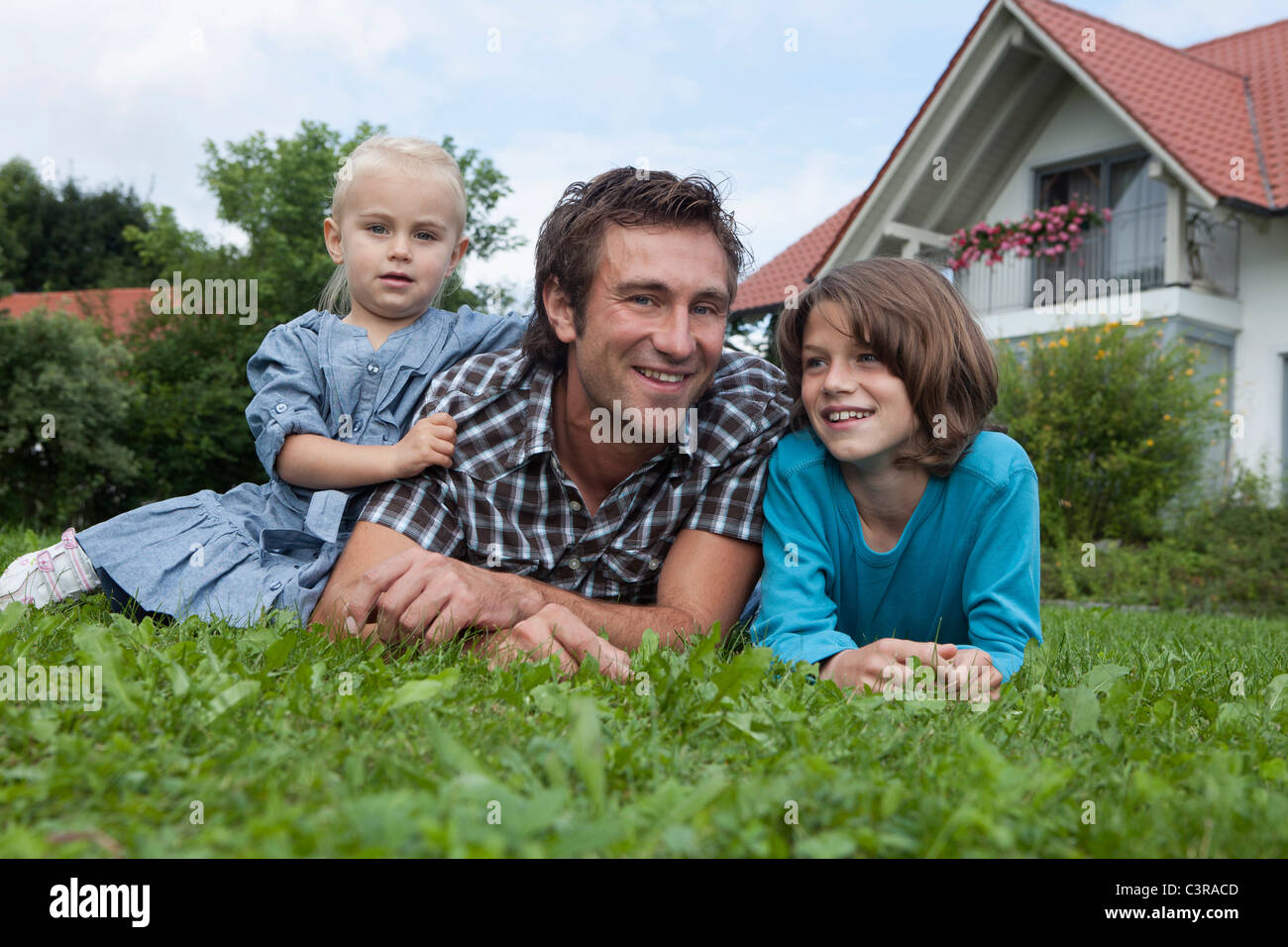 Germany, Munich, Father with children in garden, smiling Stock Photo ...