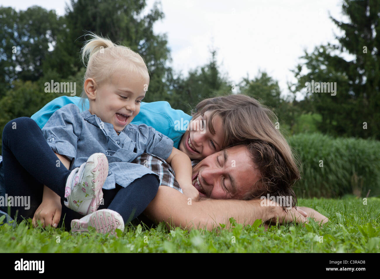 Germany, Munich, Father with children in garden, smiling Stock Photo ...