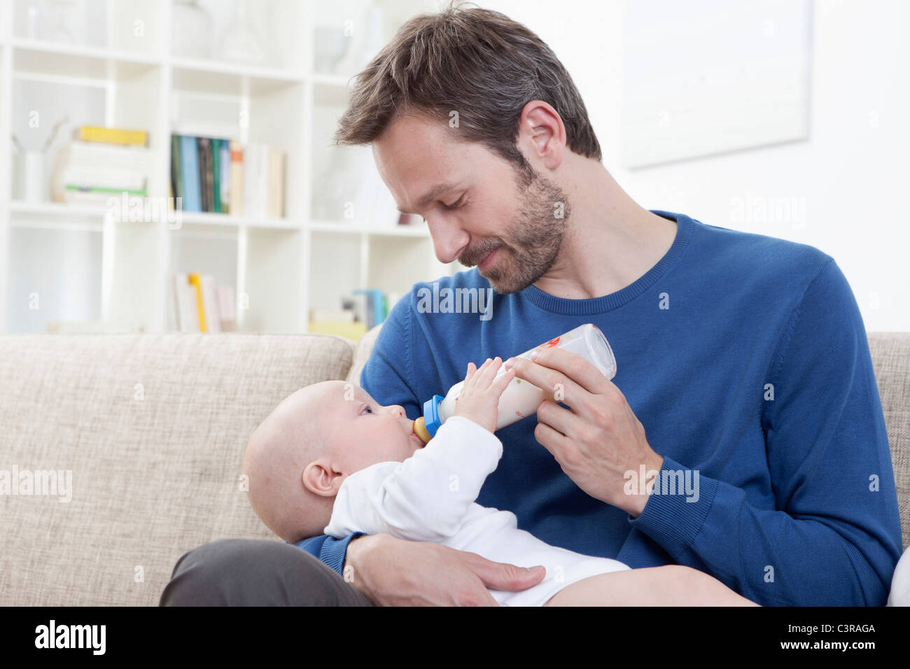 Germany, Bavaria, Munich, Father feeding milk to baby boy (6-11 Months ...