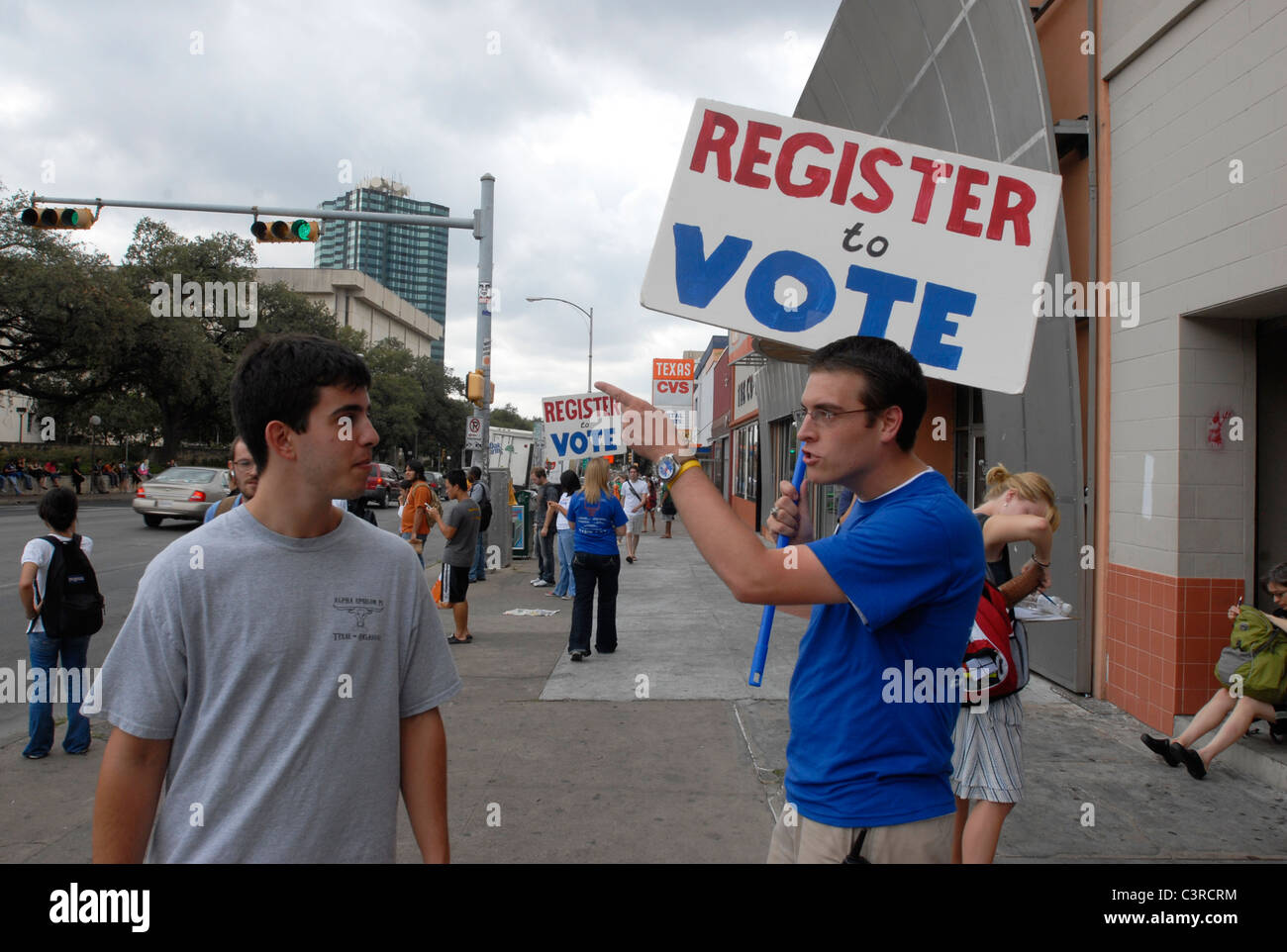Male college student holding a sign to encourage people to register to ...