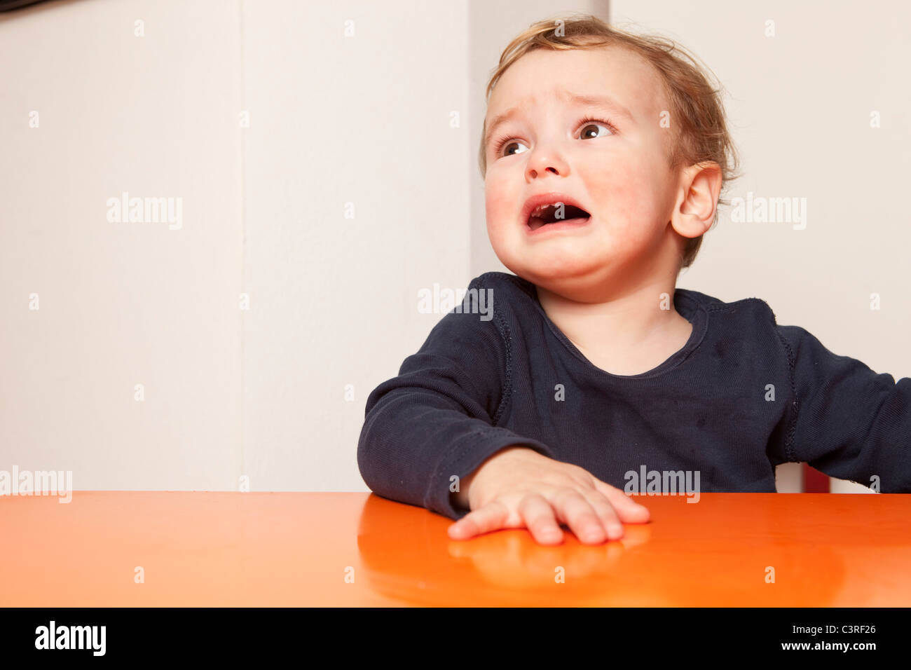Little boy sitting on table crying Stock Photo - Alamy