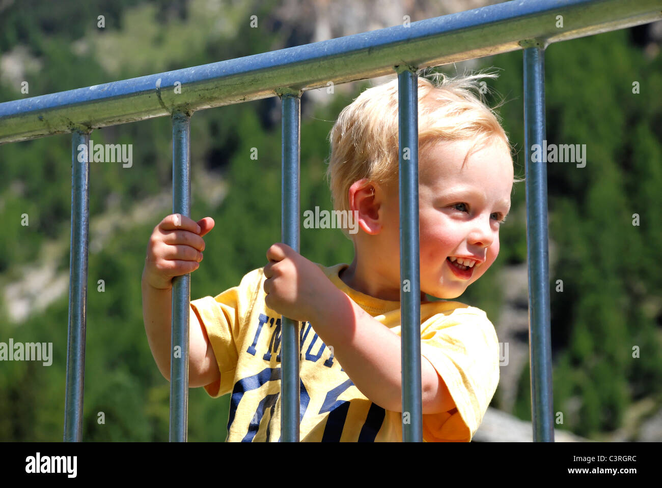 A young boy hanging onto a road side railing Stock Photo - Alamy