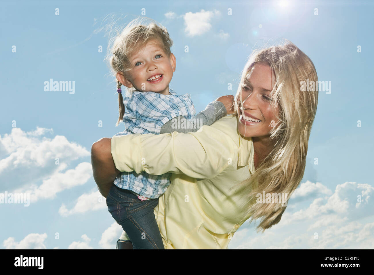 Germany, Cologne, Mother carrying her daughter (2-3 Years) on back ...