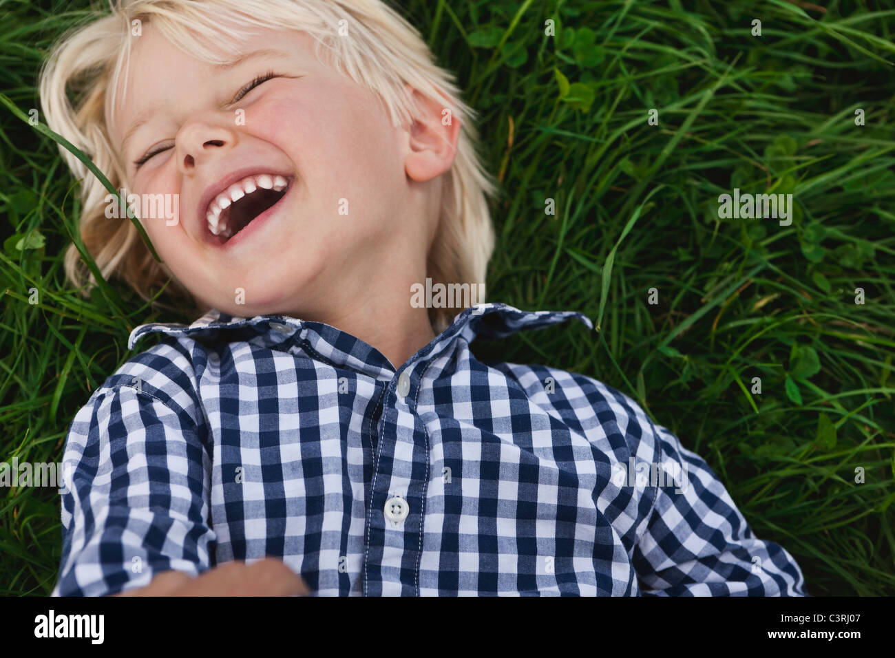 Germany, Cologne, Boy (2-3 Years) lying on grass and laughing Stock ...