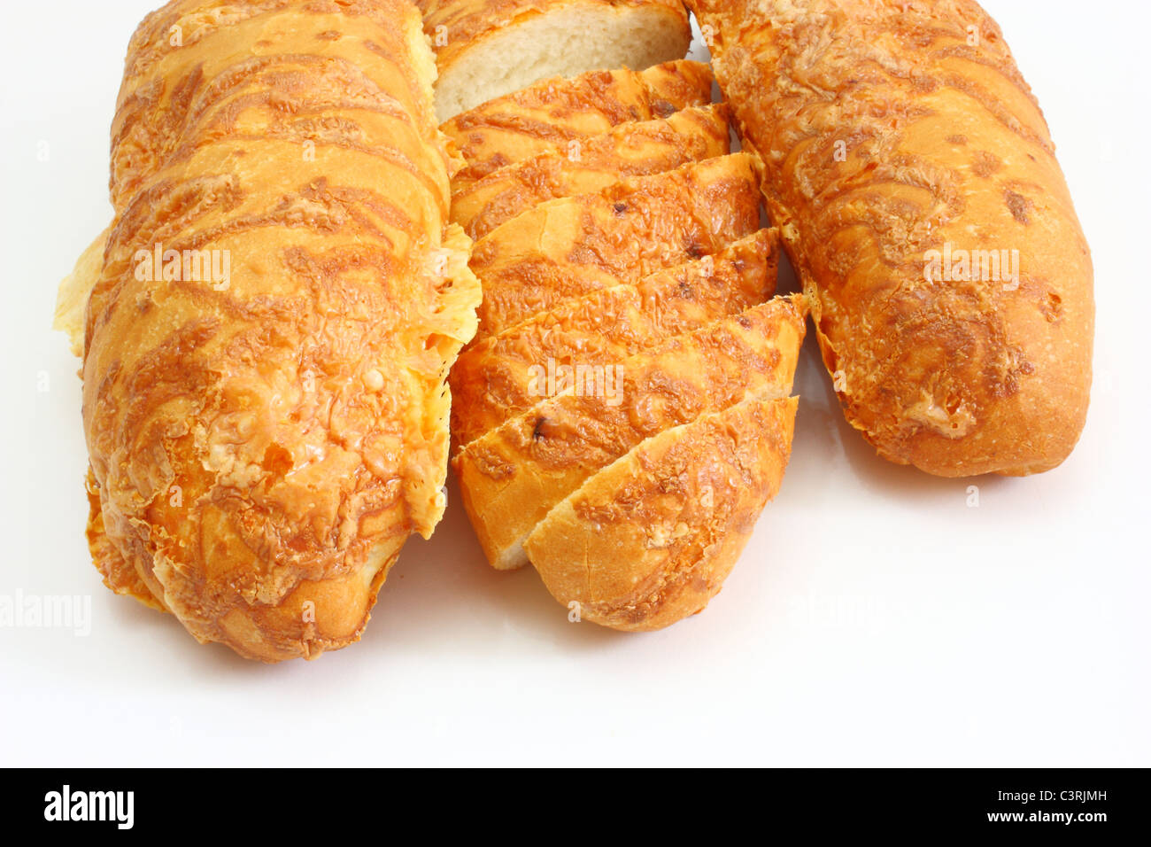 The ruddy long loaf of bread is strewed by cheese isolated on a white ...