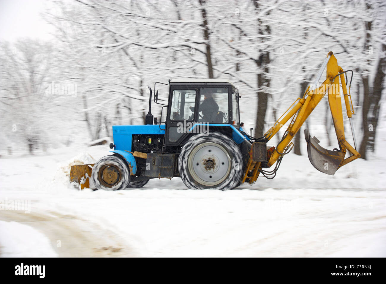 The tractor of dark blue color deletes snow in park Stock Photo - Alamy