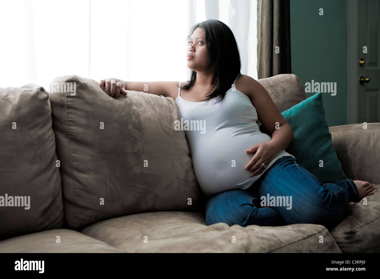 Expectant Mother sitting on couch looking out window Stock Photo - Alamy