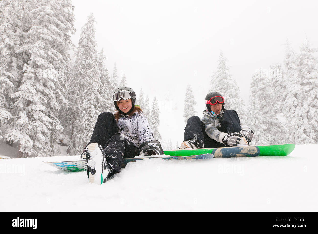 Snowboarders sitting in snow Stock Photo - Alamy
