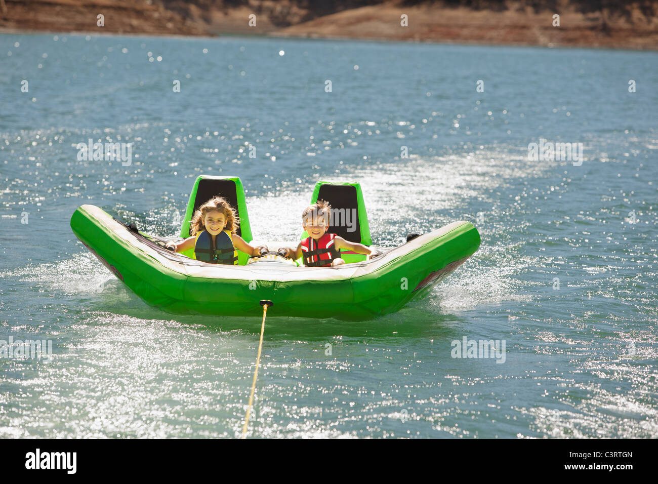 Children riding inflatable raft on lake Stock Photo - Alamy