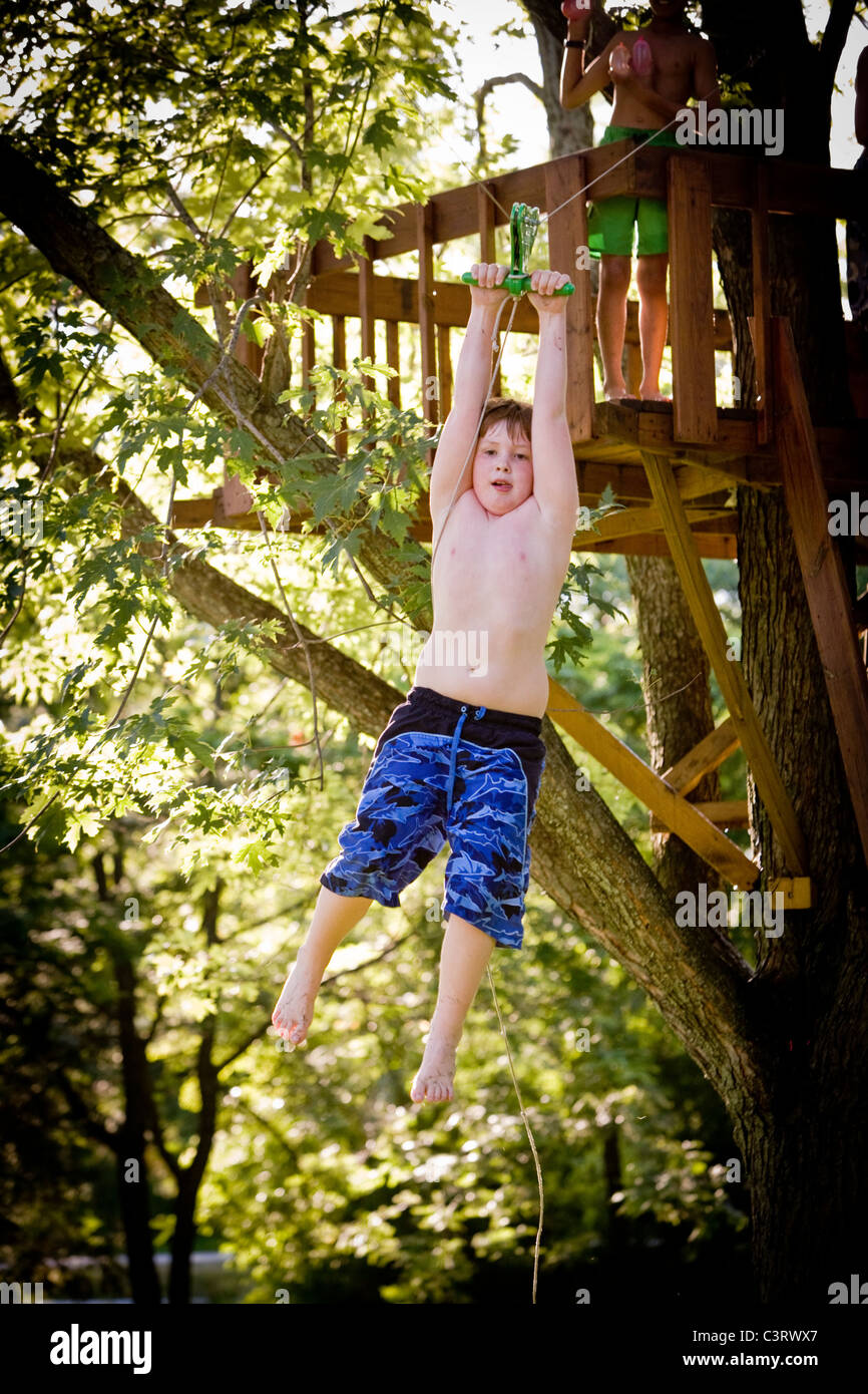 An adventurous young boy hanging from a zipline Stock Photo - Alamy