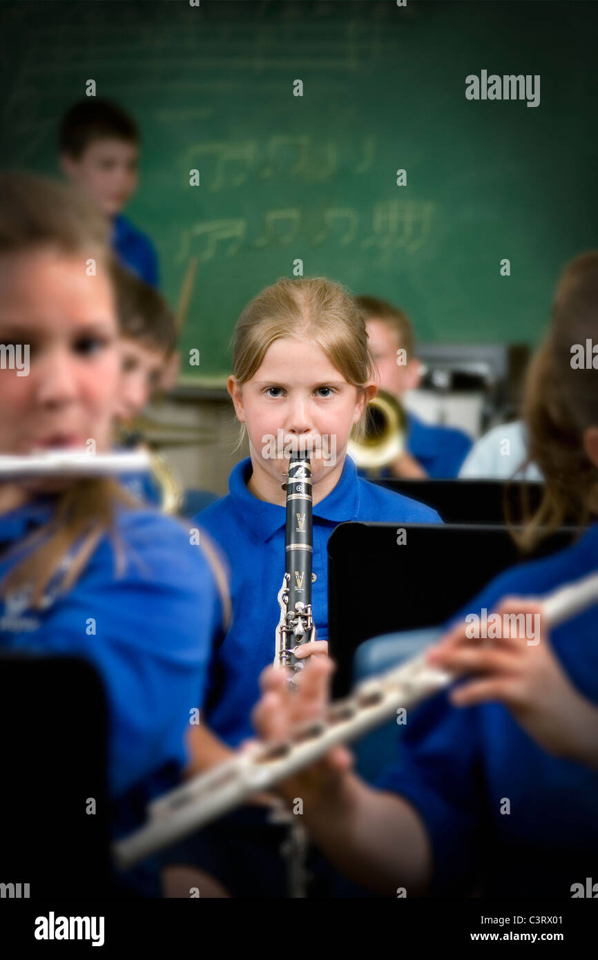 A girl plays the clarinet along with fellow students in music class ...