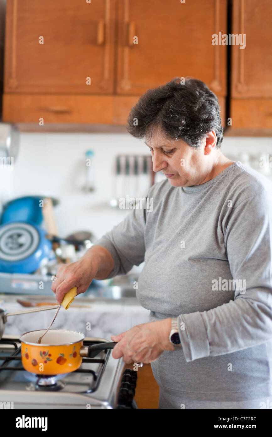Senior woman cooking on a stove in bright daylight Stock Photo - Alamy