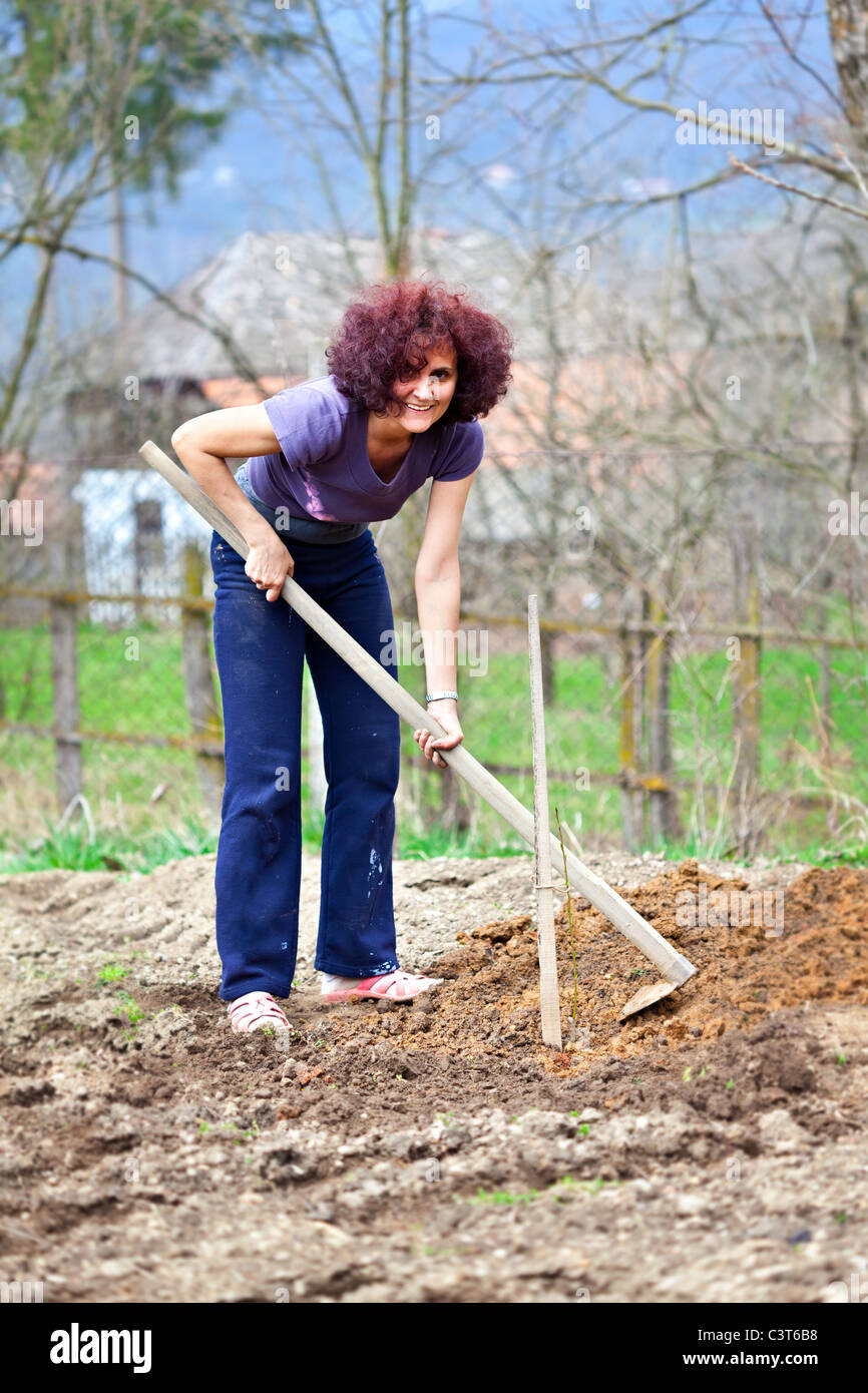 Young redhead woman digging into her garden for planting trees Stock ...