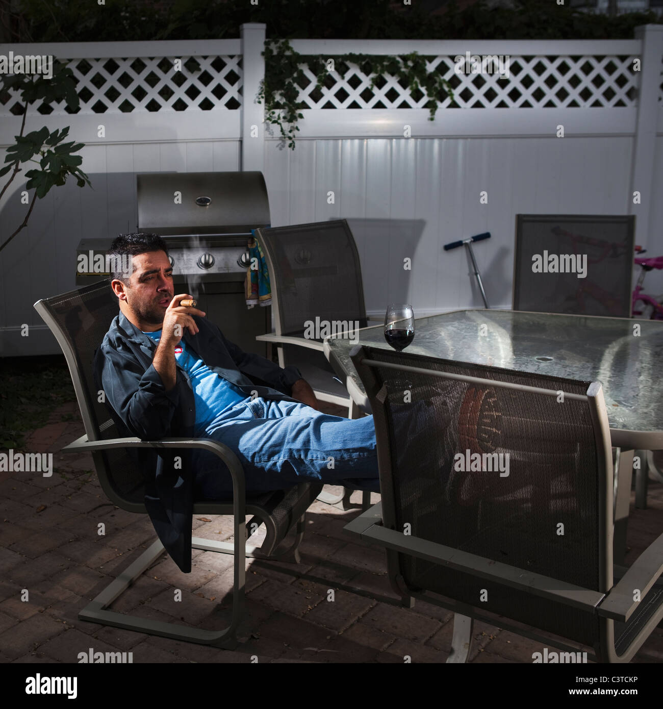 Caucasian man drinking wine and smoking on patio Stock Photo - Alamy