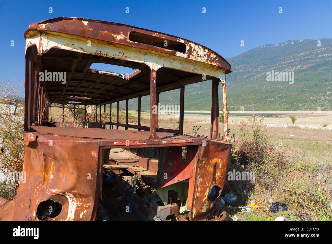 stripped rusty, old abandoned bus wreck in arid mountainous landscape ...