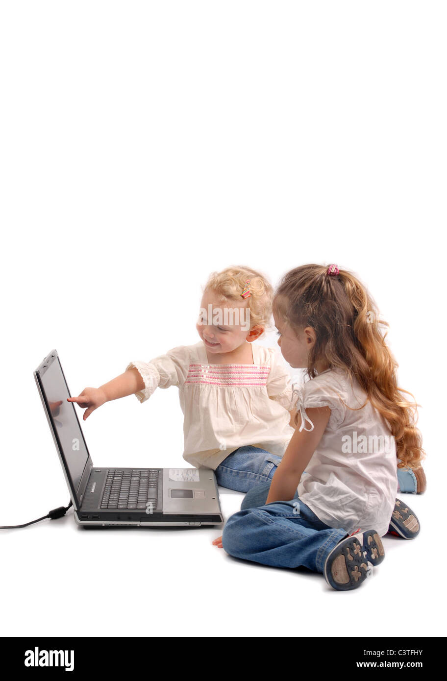 Little girl and baby sister touching a notebook screen on white ...