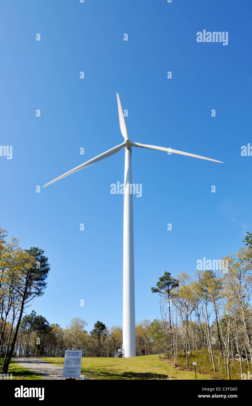 Looking up at a wind turbine surrounded by trees and woods on a clear ...