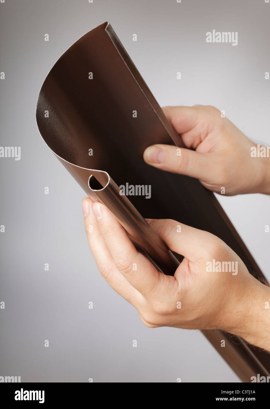 Man holding old-fashioned brown piece of rain gutter in his hands Stock ...