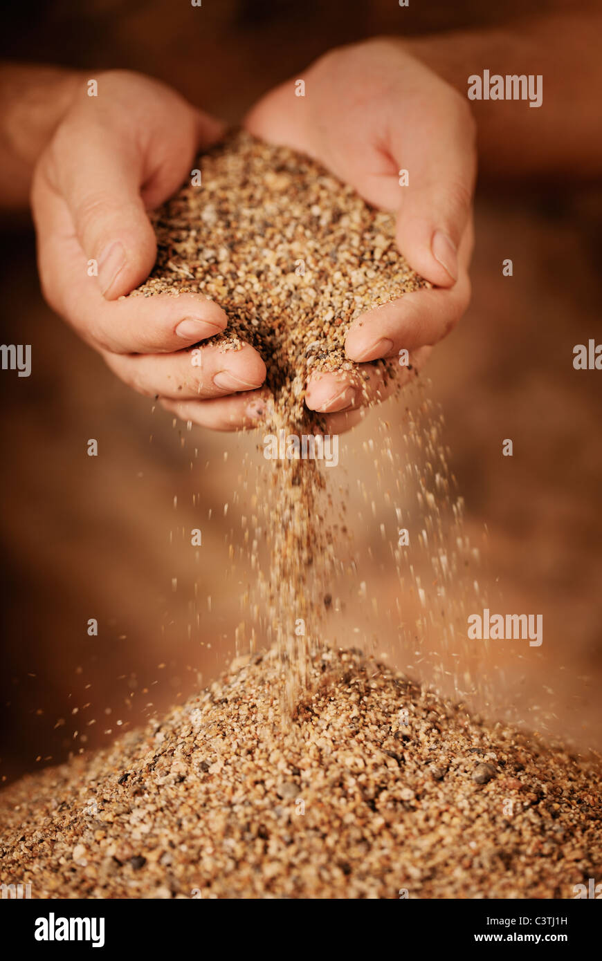 Man adding coarse sand to a heap with his hands. Very shallow depth-of ...