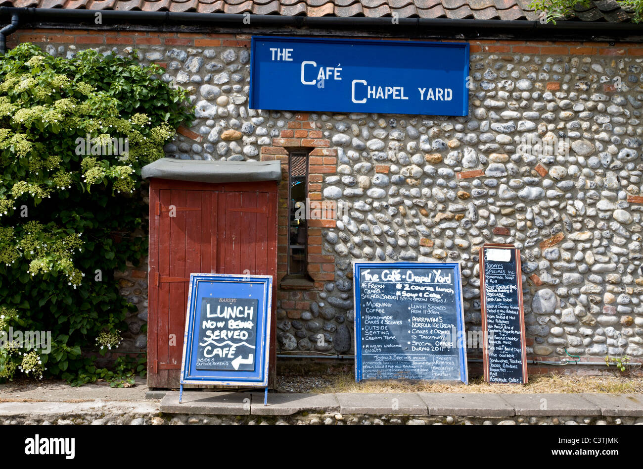 Café and restaurant signs against a cobbled wall. Norfolk, England, UK ...