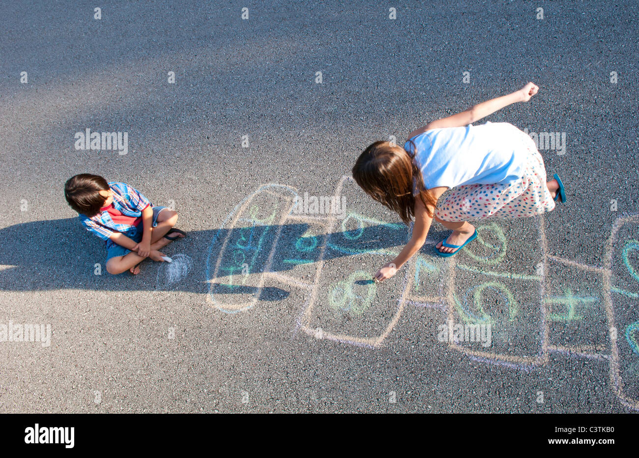 Graphic angle of young girl playing hopskotch on pavement from above ...