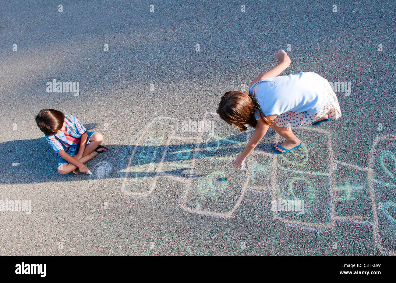 Graphic angle of young girl playing hopskotch on pavement from above ...