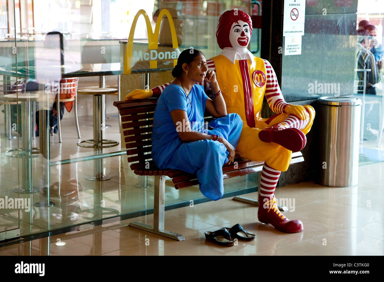 Indian woman sitting on bench at McDonald's fast food restaurant ...