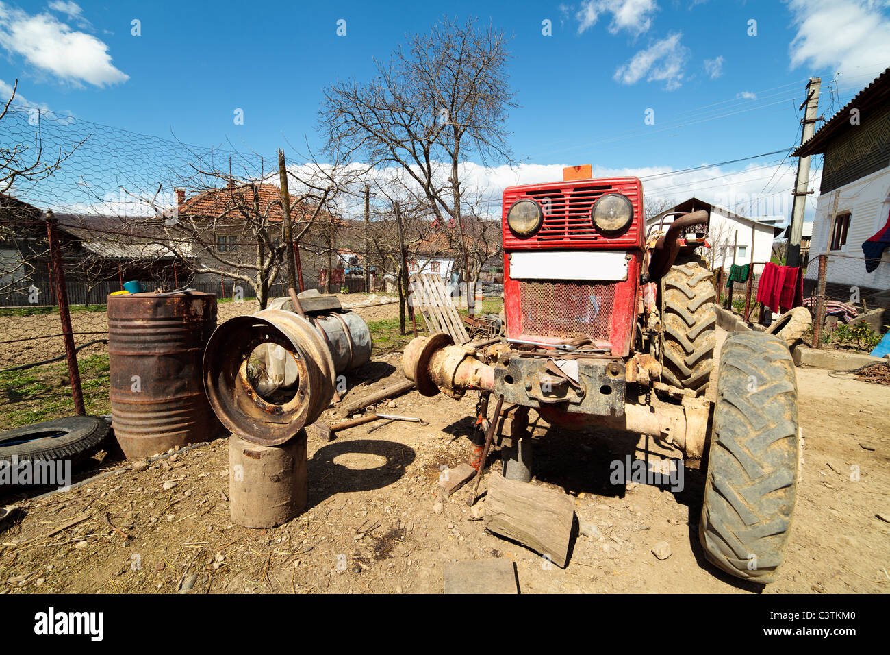 Old broken red tractor in a court in the countryside, to be repaired ...