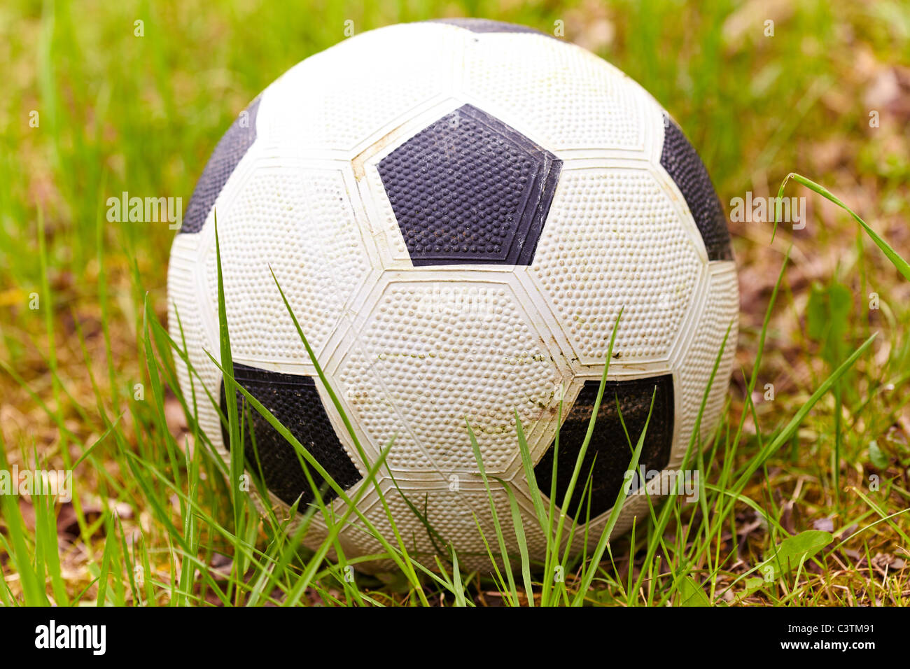 Worn football ball in a grass field Stock Photo - Alamy