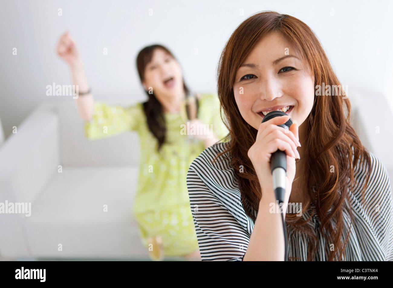 Two Women Singing Karaoke and Having Champagne Stock Photo - Alamy